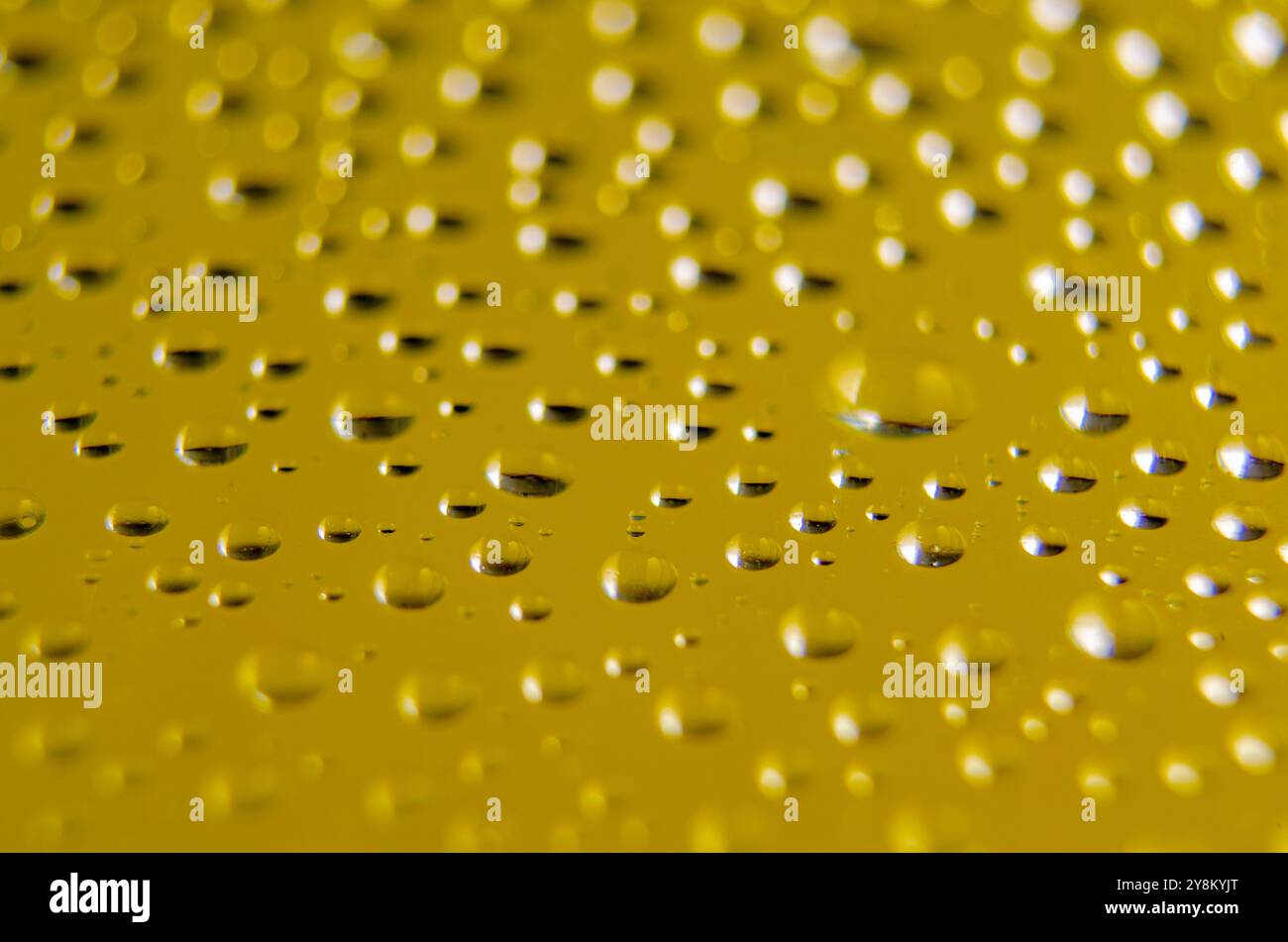 Side view of raindrops forming patterns on a smooth surface on yellow ...