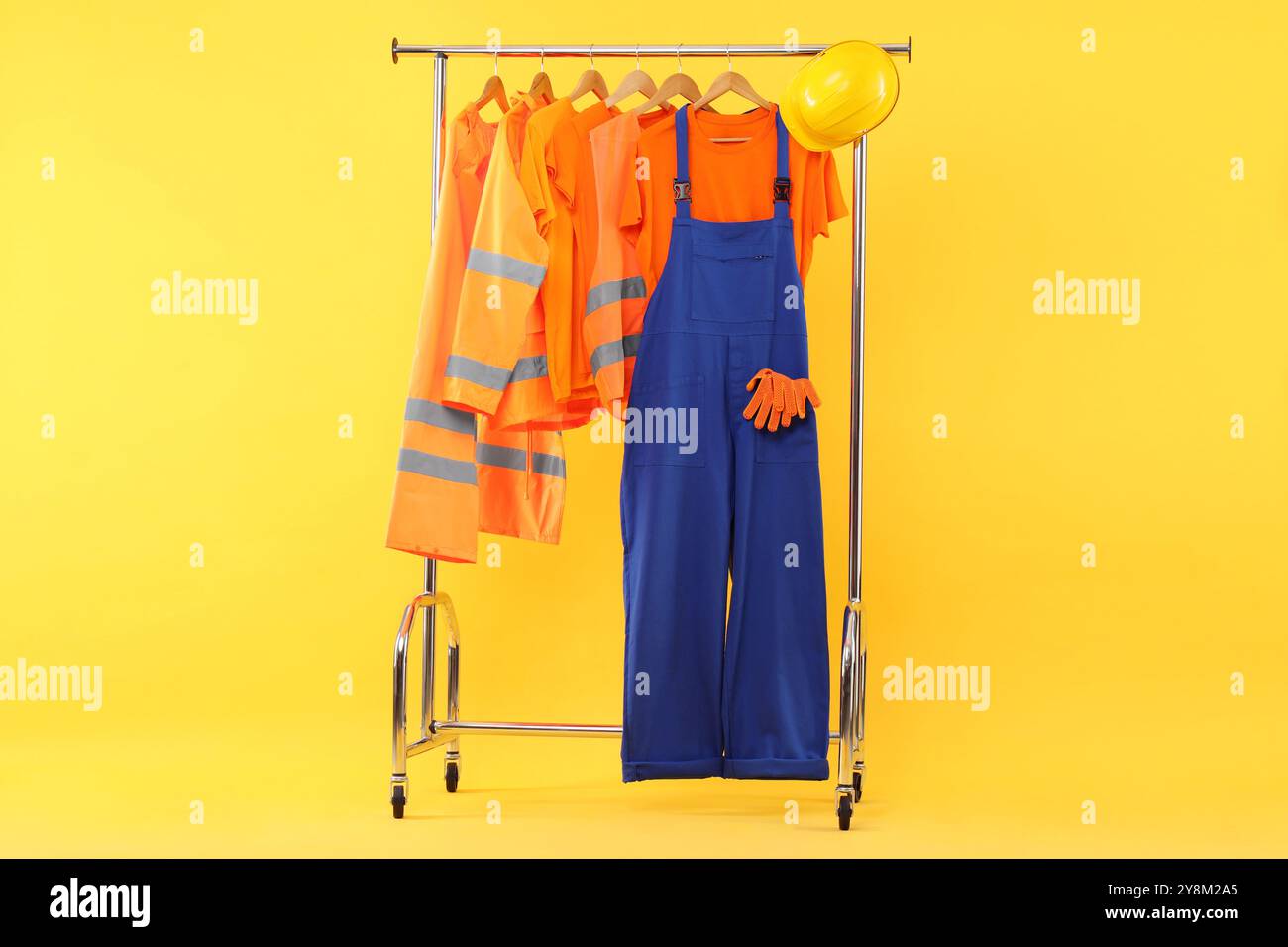 Workers' uniforms on clothing rack against yellow background Stock ...