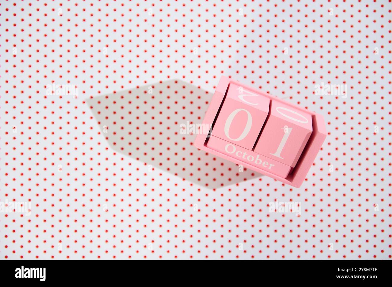 A pink block calendar displaying October 1st on a backdrop of red polka ...