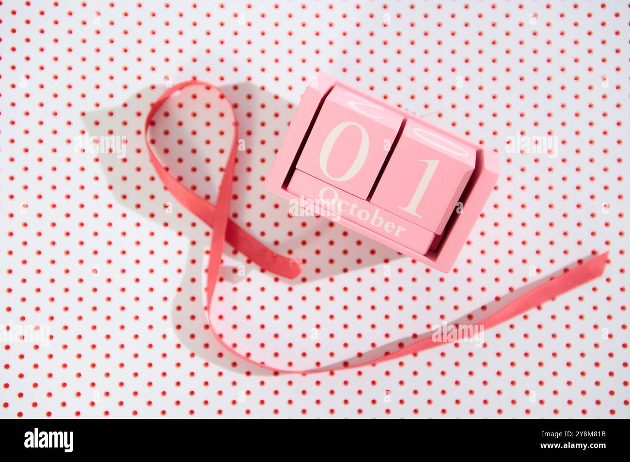 Pink cube calendar displaying October 1st, accompanied by a ribbon on a ...