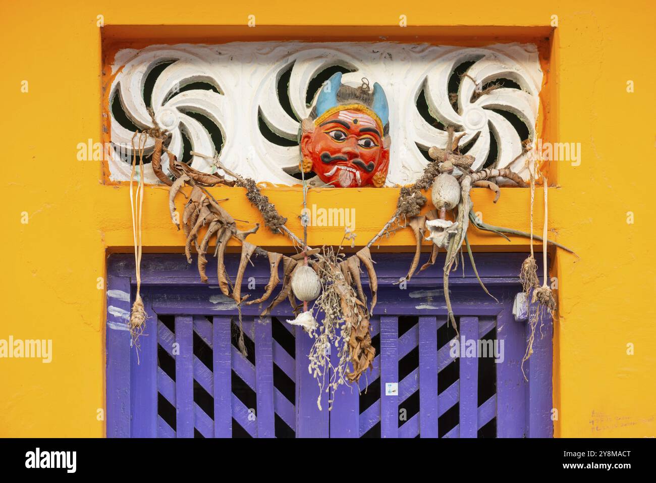 Purple-coloured front door, yellow wall, house entrance with demon mask ...