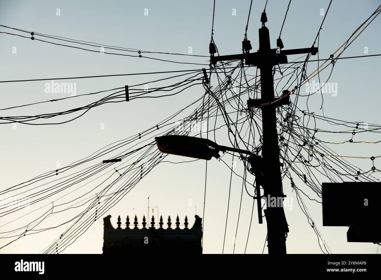 High-voltage power lines, tangle of cables, temple gopura or temple ...