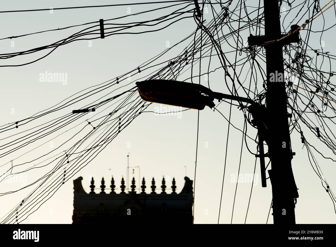 High-voltage power lines, tangle of cables, temple gopura or temple ...