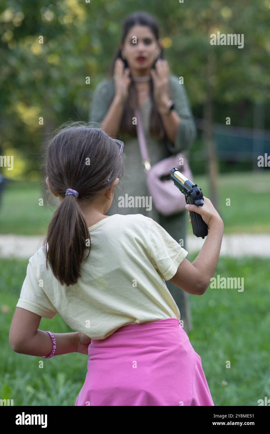 Little girl with gun terrorizes her mother. Concept of danger of ...