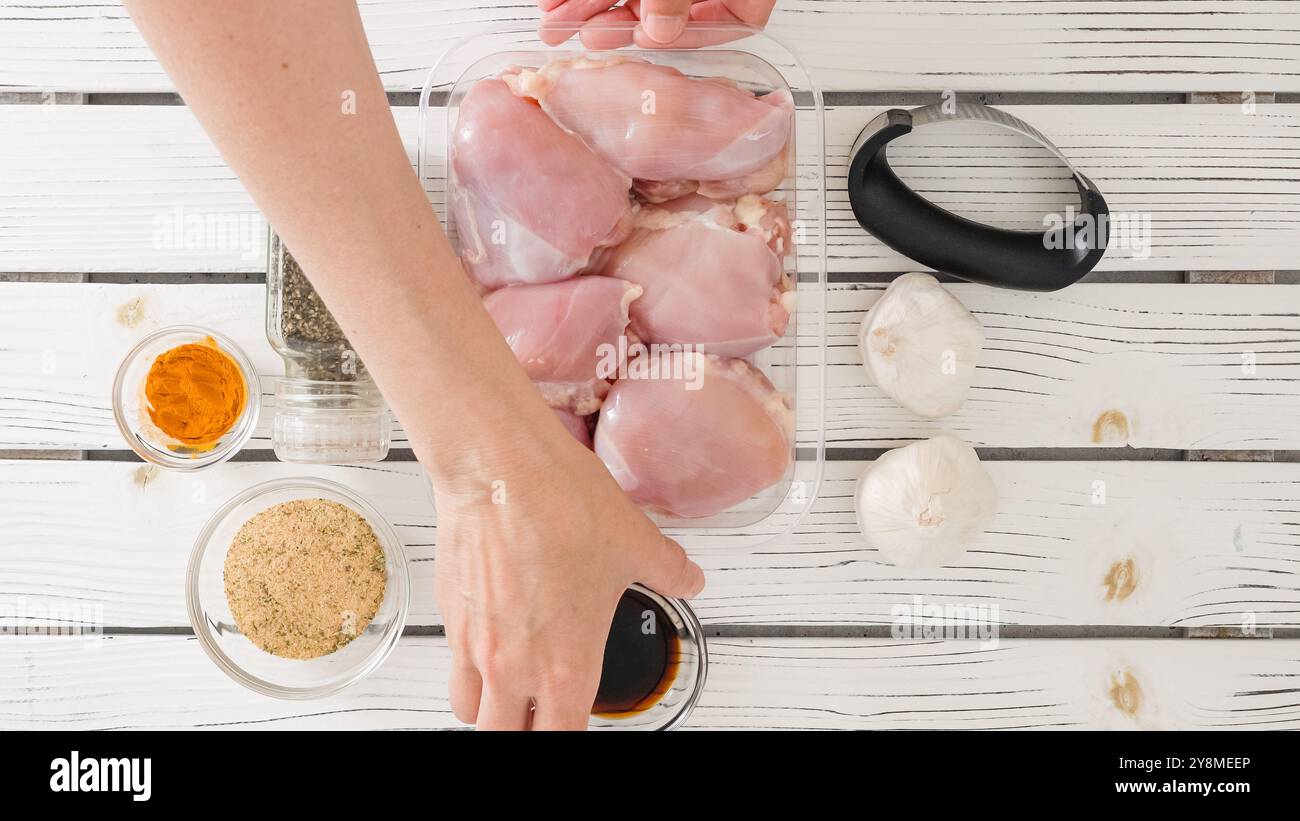 Chef marinating chicken thighs with soy sauce, turmeric, black pepper ...