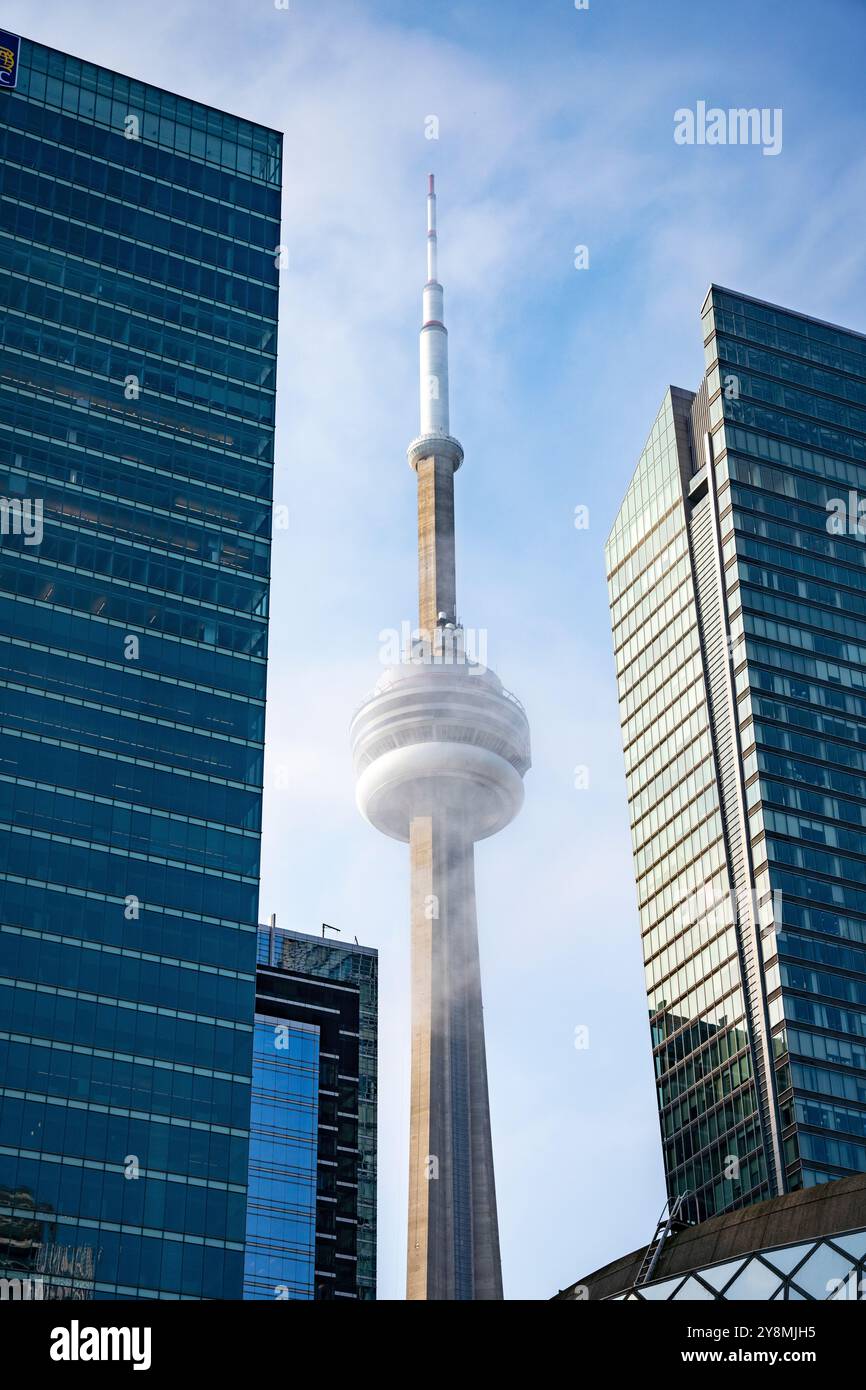 The CN Tower in Toronto emerges from the mist between two skyscrapers ...
