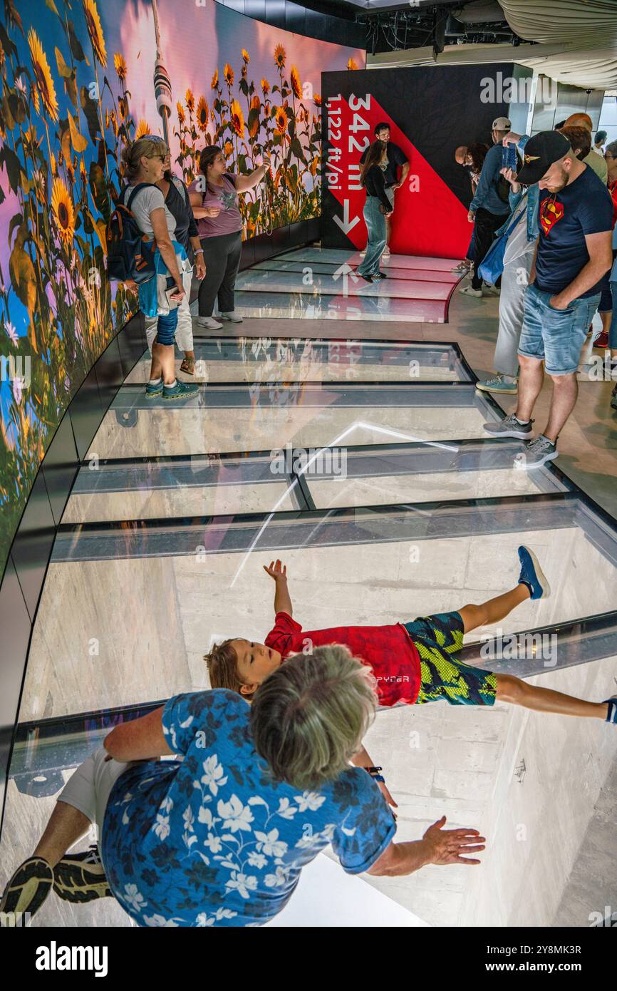 Visitors lie on the glass floor observation deck at the CN Tower ...