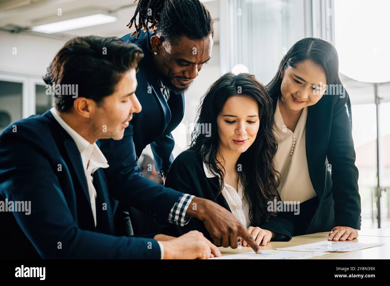 International business professionals gather in a meeting room, led by a female boss. Their ...