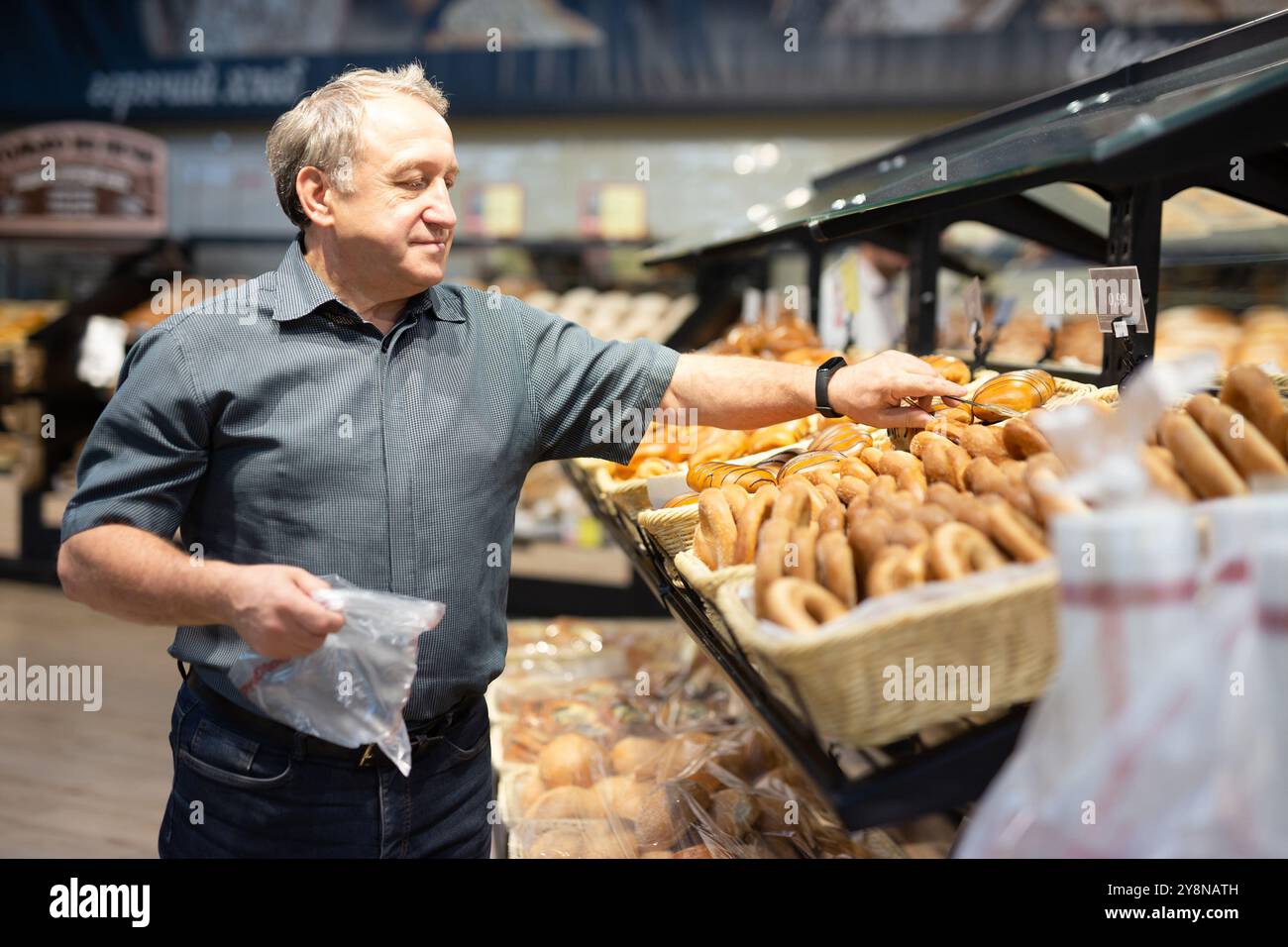 Man takes muffins on shelf of bakery section Stock Photo - Alamy