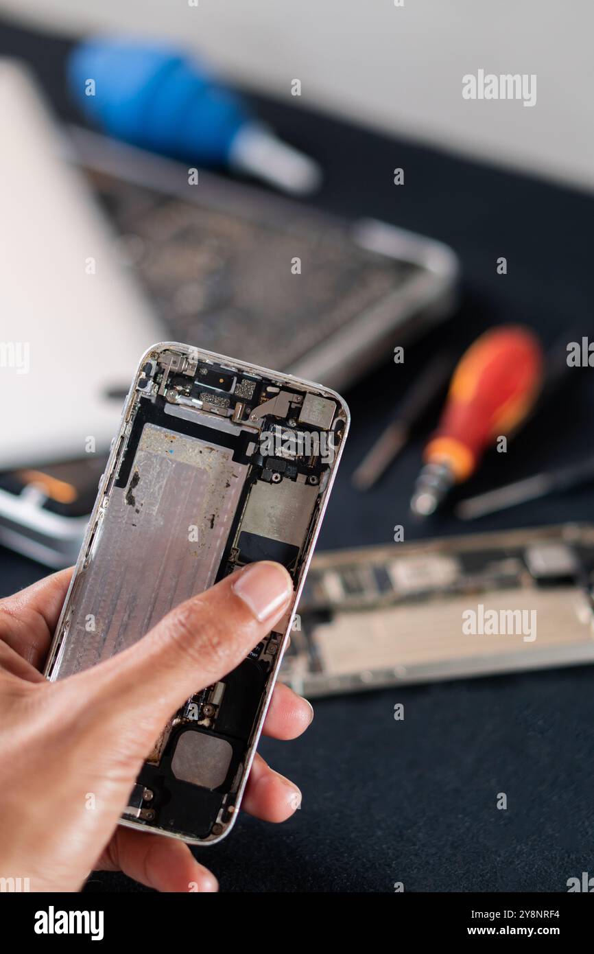 A close-up of a person holding a disassembled smart phone, revealing ...