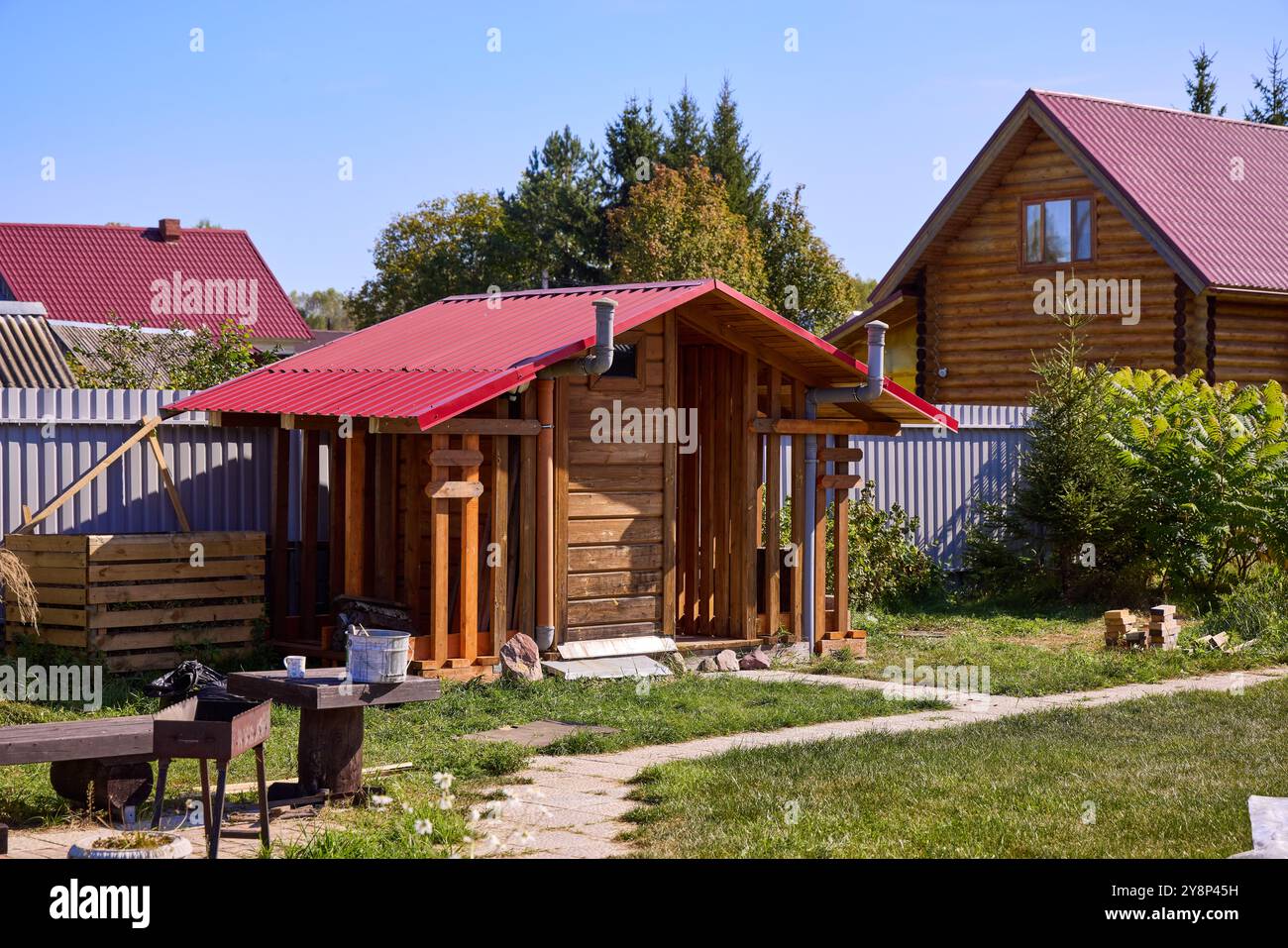 A traditional wooden outhouse with a red roof, located in a rural area ...