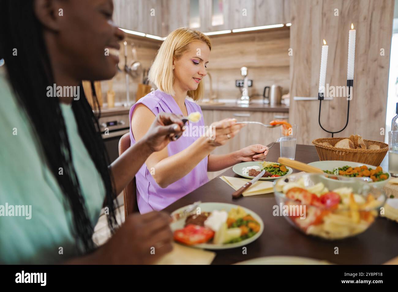 Friends enjoying a delicious homemade meal in a cozy kitchen Stock ...