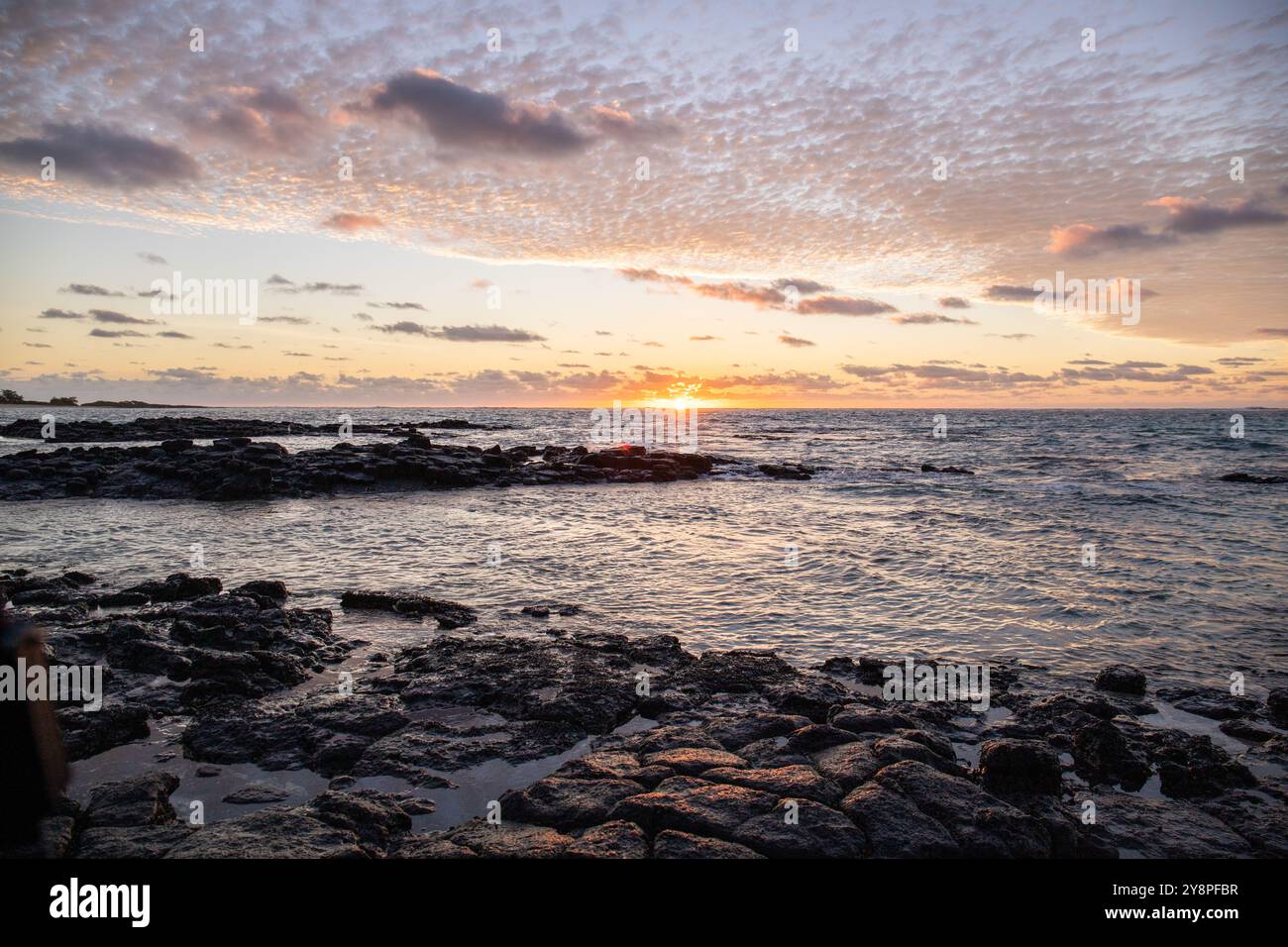 Sunrise over the sea. Sandy beach with lava rocks and beach alternate ...