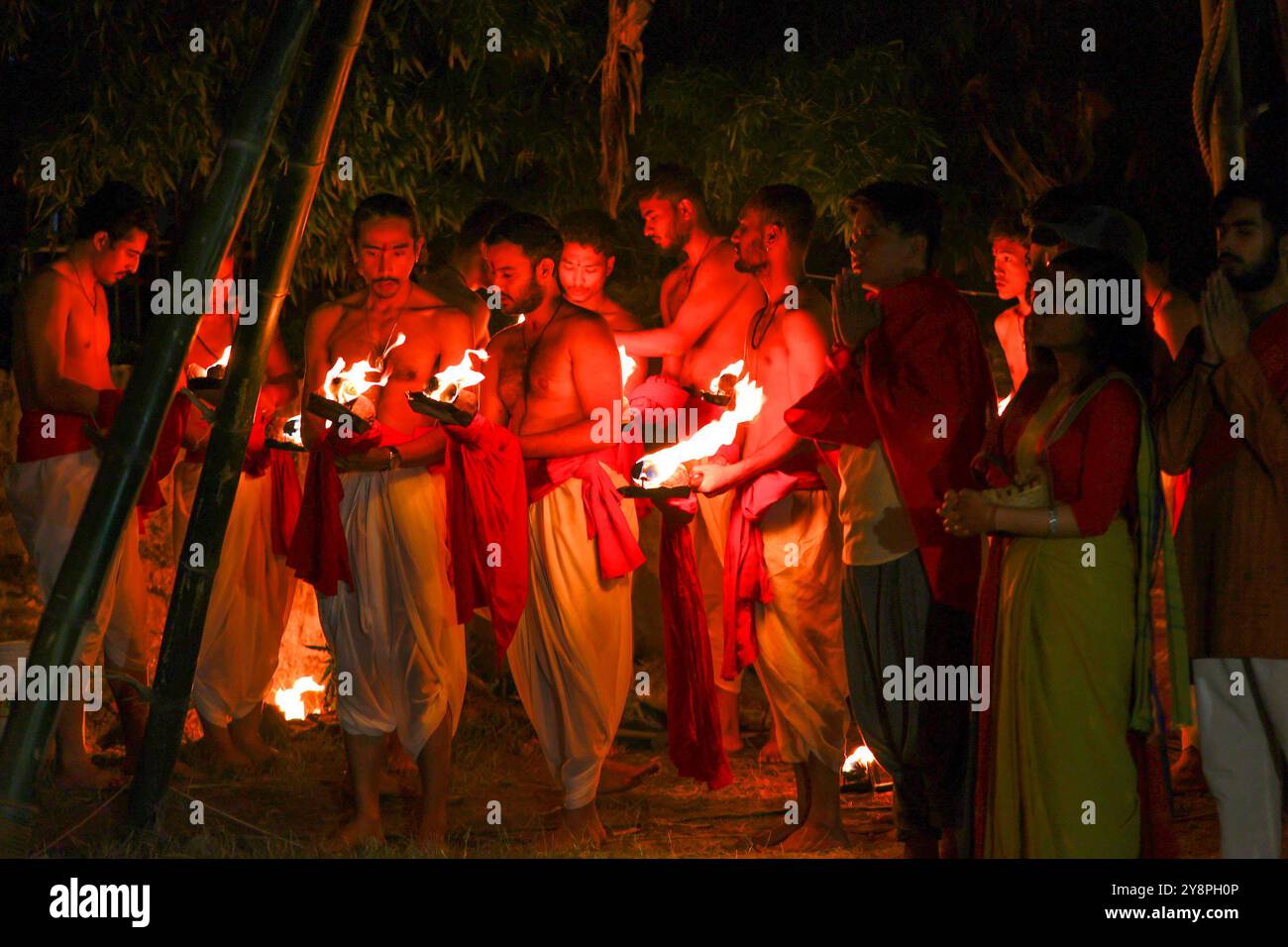 Devotees dressed in traditional attires flicker oil lamps as they ...