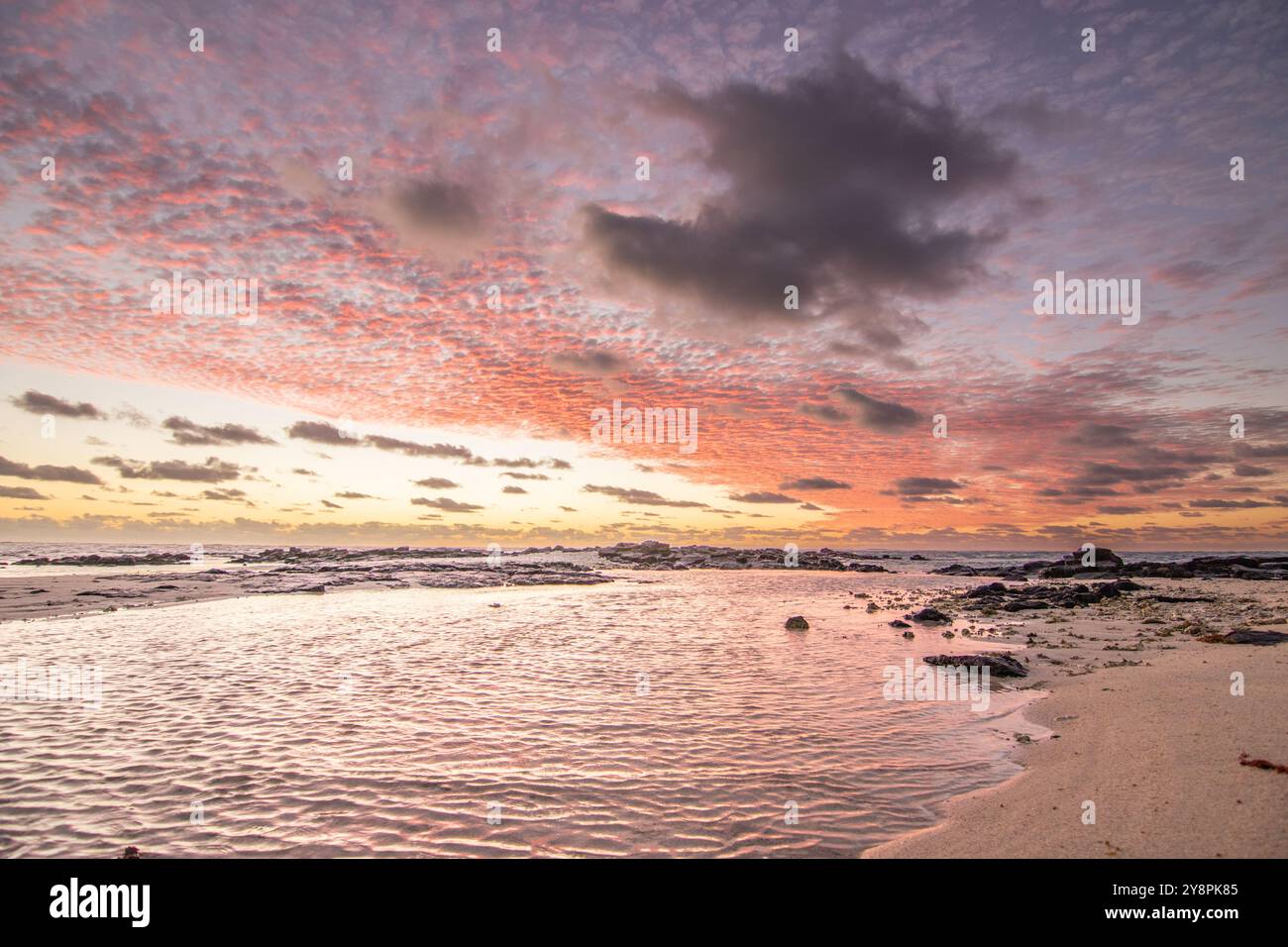 Sunrise over the sea. Sandy beach with lava rocks and beach alternate ...