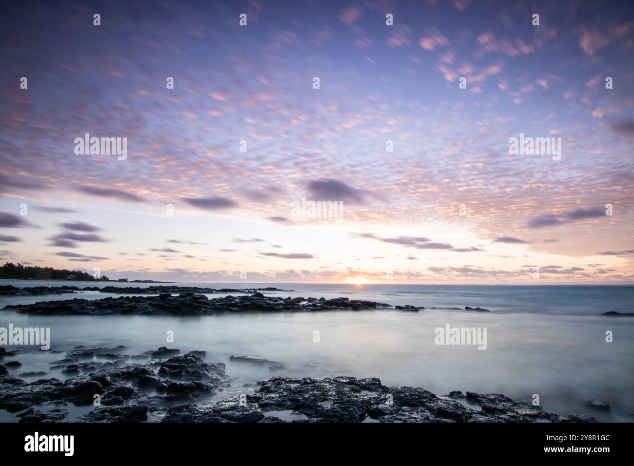 Sunrise over the sea. Sandy beach with lava rocks and beach alternate ...