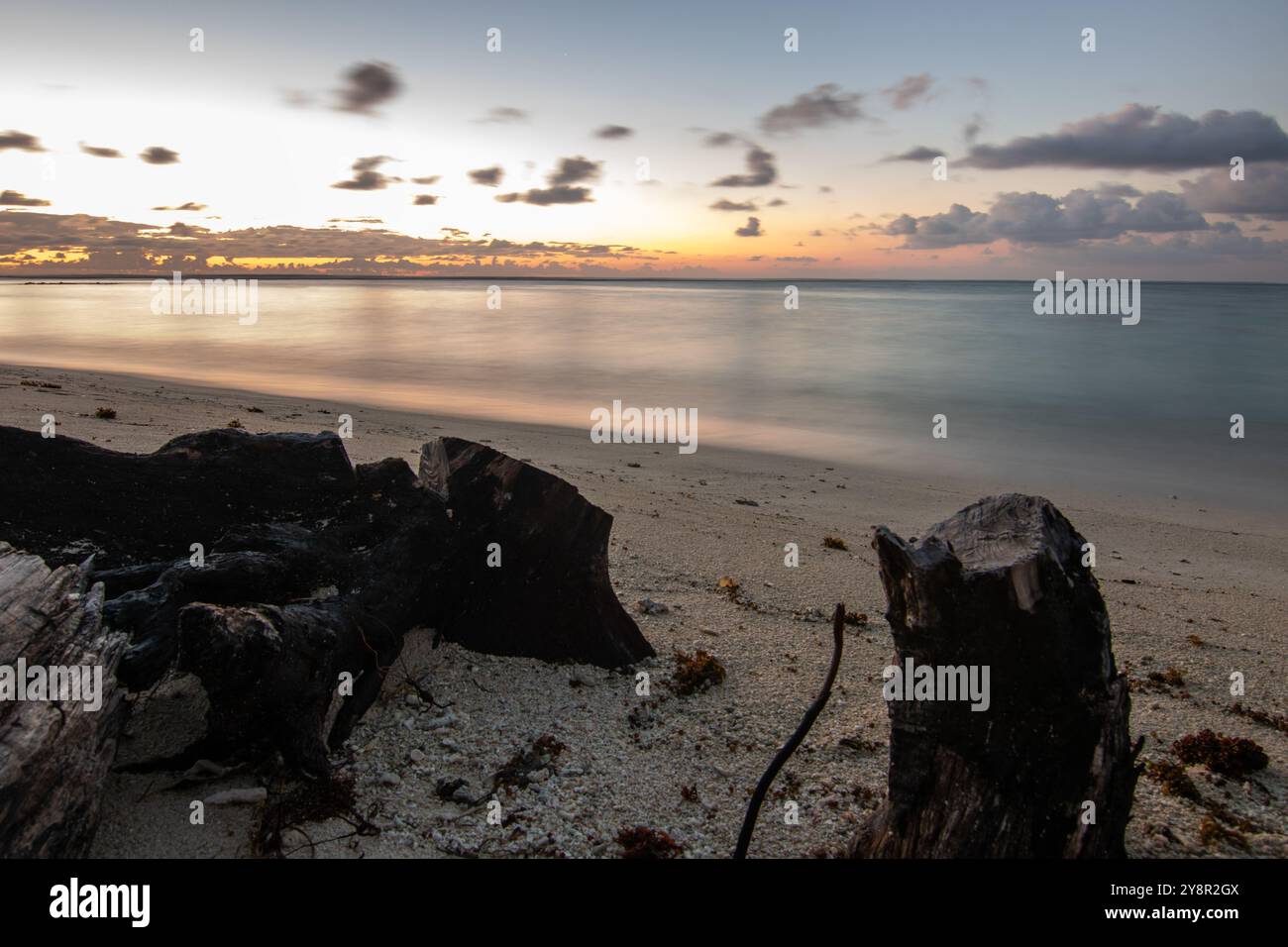Sunrise over the sea. Sandy beach with lava rocks and beach alternate ...