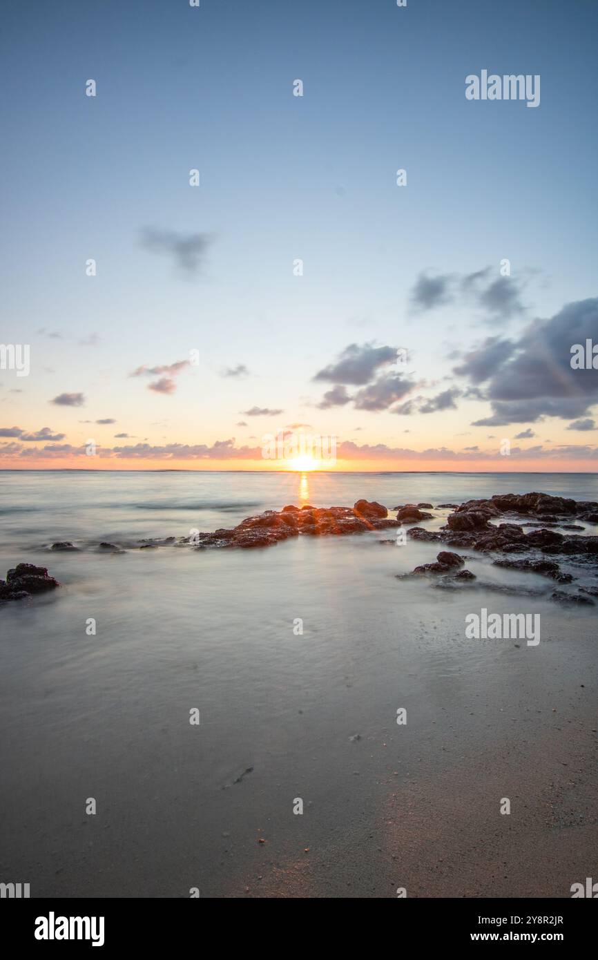 Sunrise over the sea. Sandy beach with lava rocks and beach alternate ...
