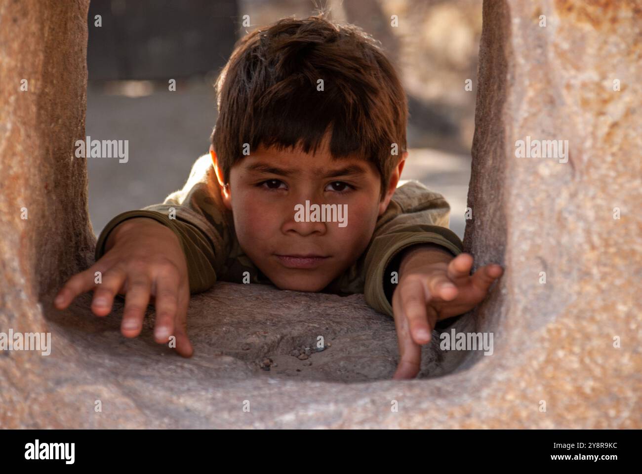 A portrait of a mexican boy with dark hair lying on a rock Stock Photo ...