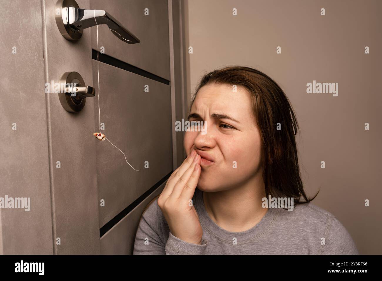 The girl is holding a thread to pull out a tooth. Extraction of a tooth ...