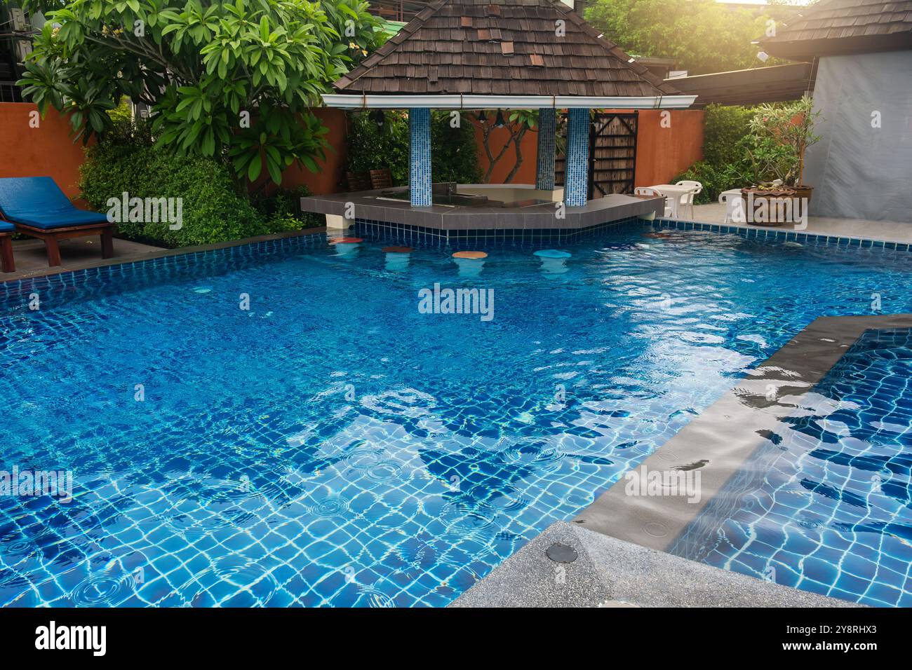 Tropical resort swimming pool with clear blue water and swim-up bar with seating area shaded by ...