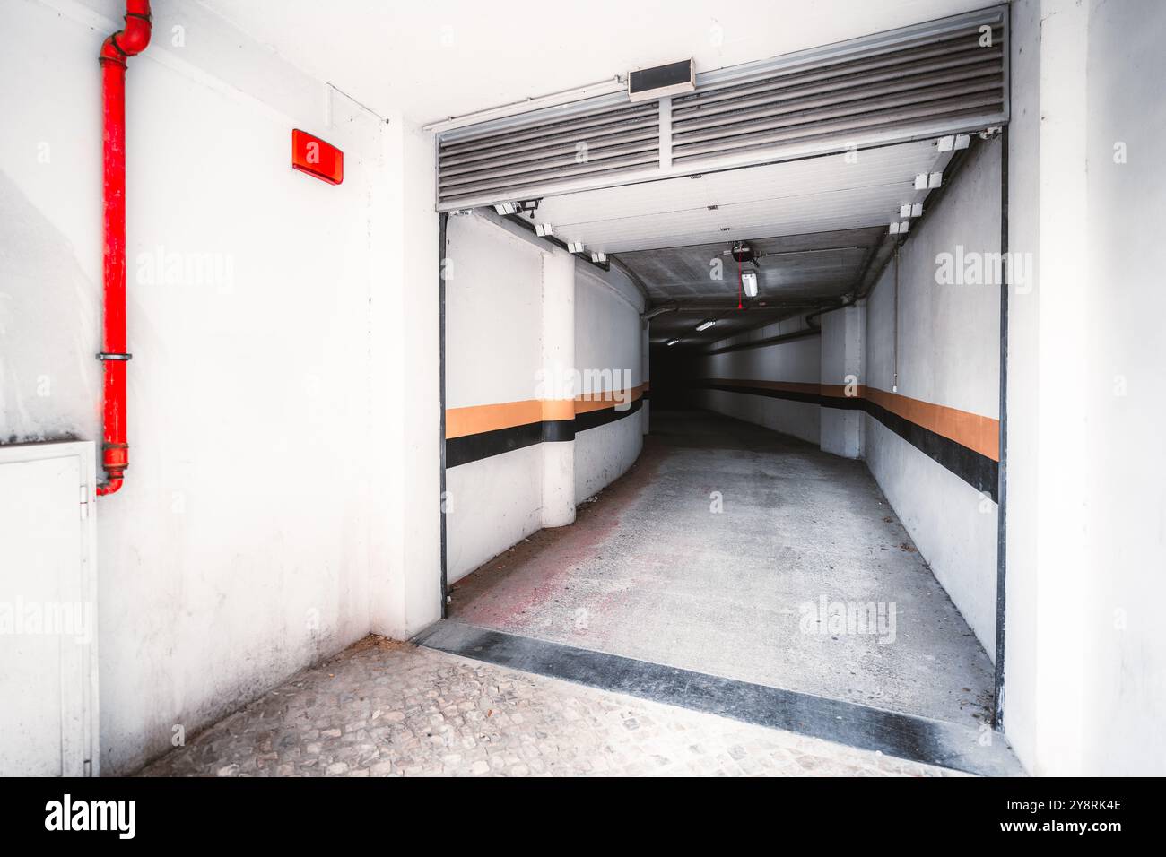 A white underground garage entrance with curved walls, featuring orange ...