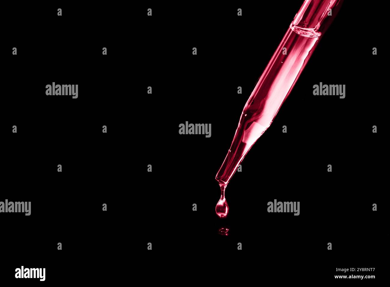 a drop of oil falling from a glass pipette. cosmetology, chemistry ...