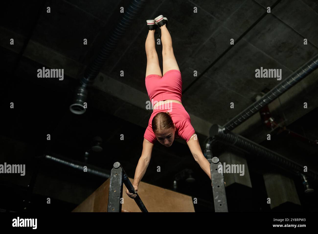 Low angle shot of professional female athlete in handstand on parallel ...