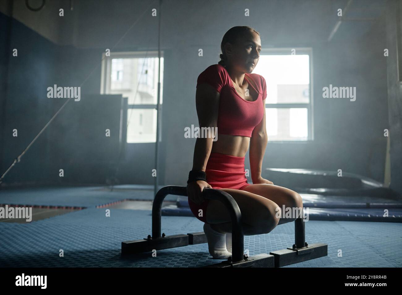 Athletic female gymnast in seated position getting ready to perform ...