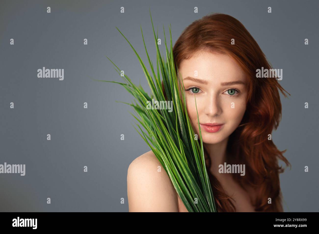 Pretty Ginger-Haired Girl Posing With Green Plant Leaves, Gray ...