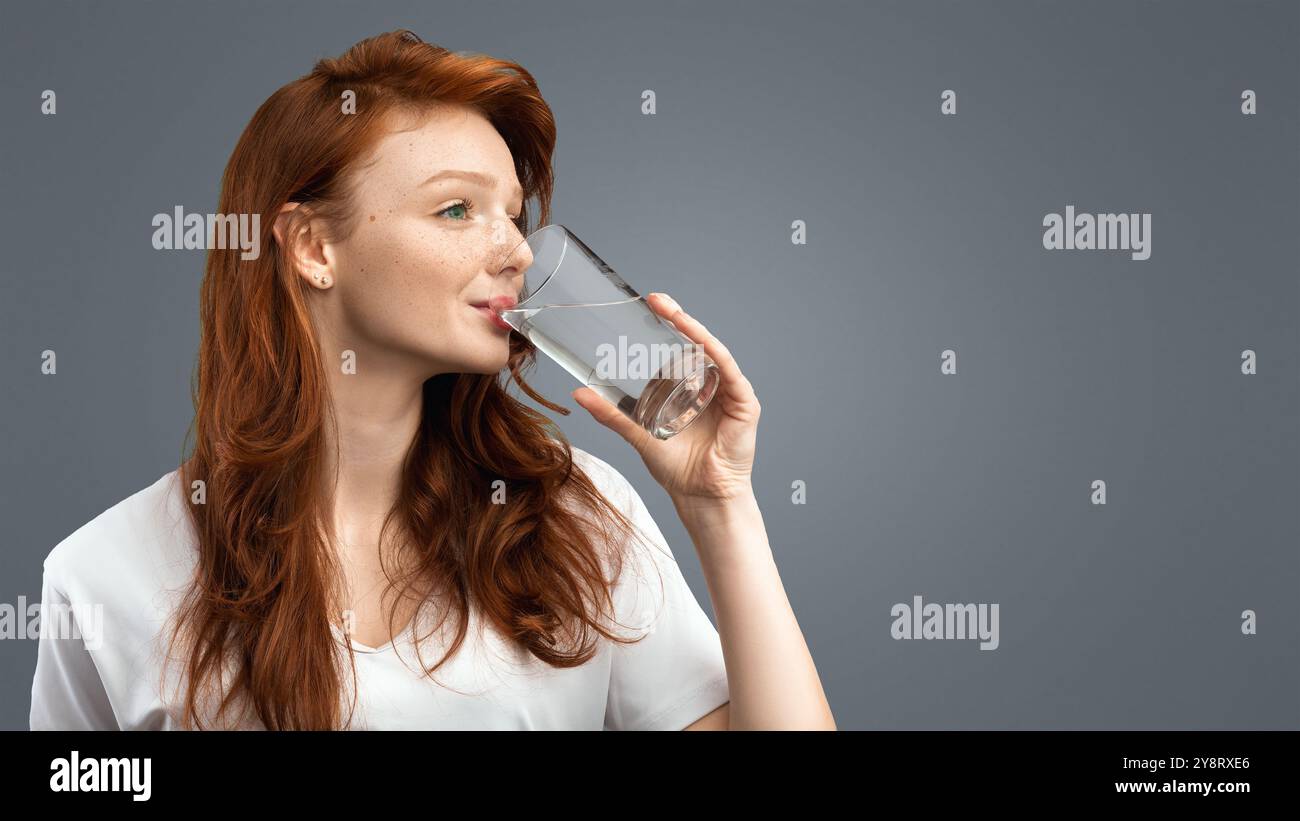 Red-Haired Millennial Woman Drinking Water From Glass, Gray Background ...