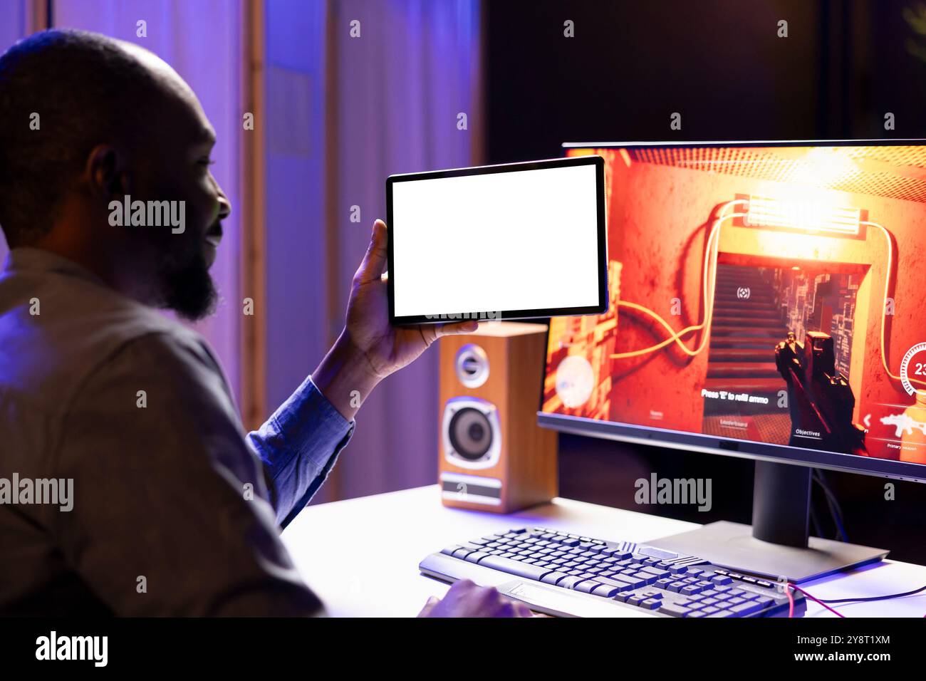 African american man holding mockup tablet in dark living room while ...
