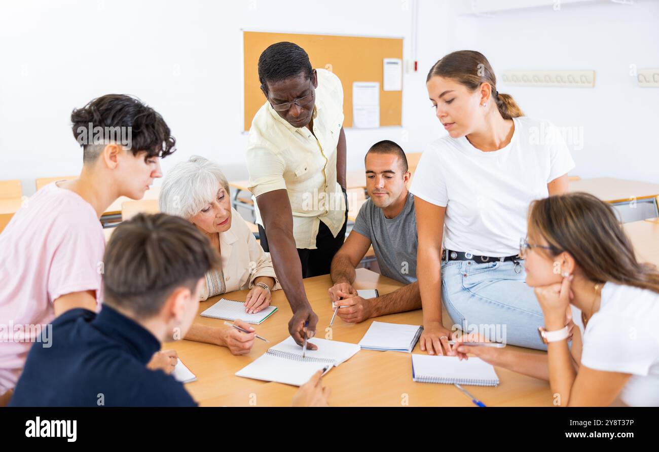 African american male teacher, together with students of different ages, conducts intensive ...
