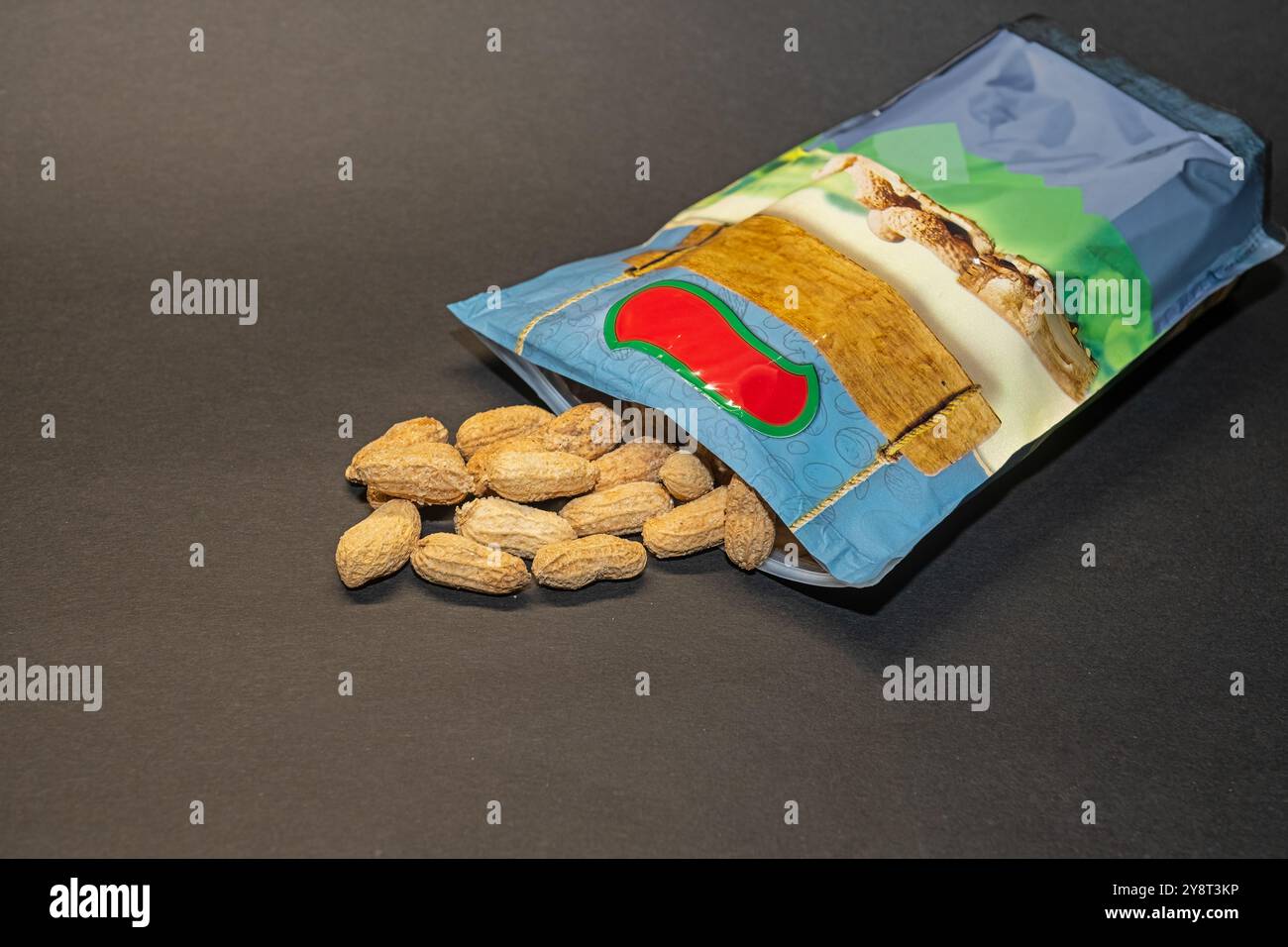 Shelled peanuts falling out of the packaging on a grey background Stock ...