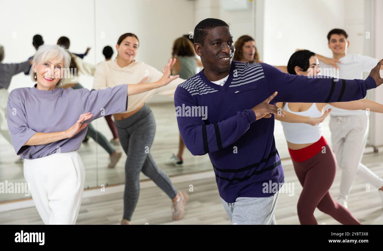 African-american guy practising dance moves with other people in dance ...