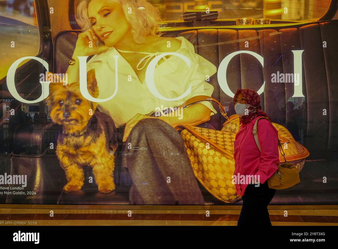 A women walks by a Gucci advertisement board in Kuala Lumpur. Brand and ...