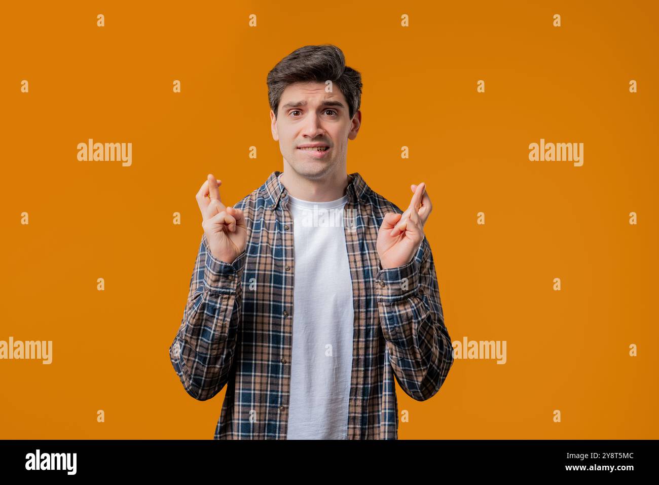 Adult 30s man praying with crossed fingers on yellow background. Guy ...