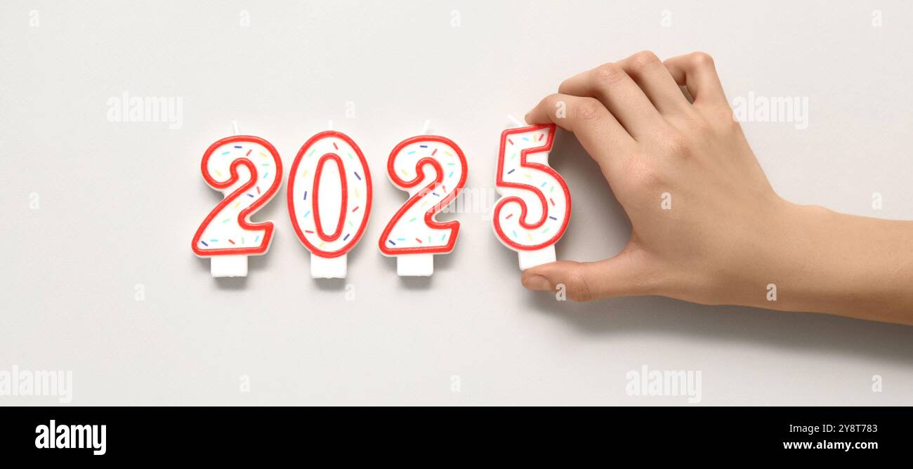 Female hand with candles in shape of figure 2025 on light background ...