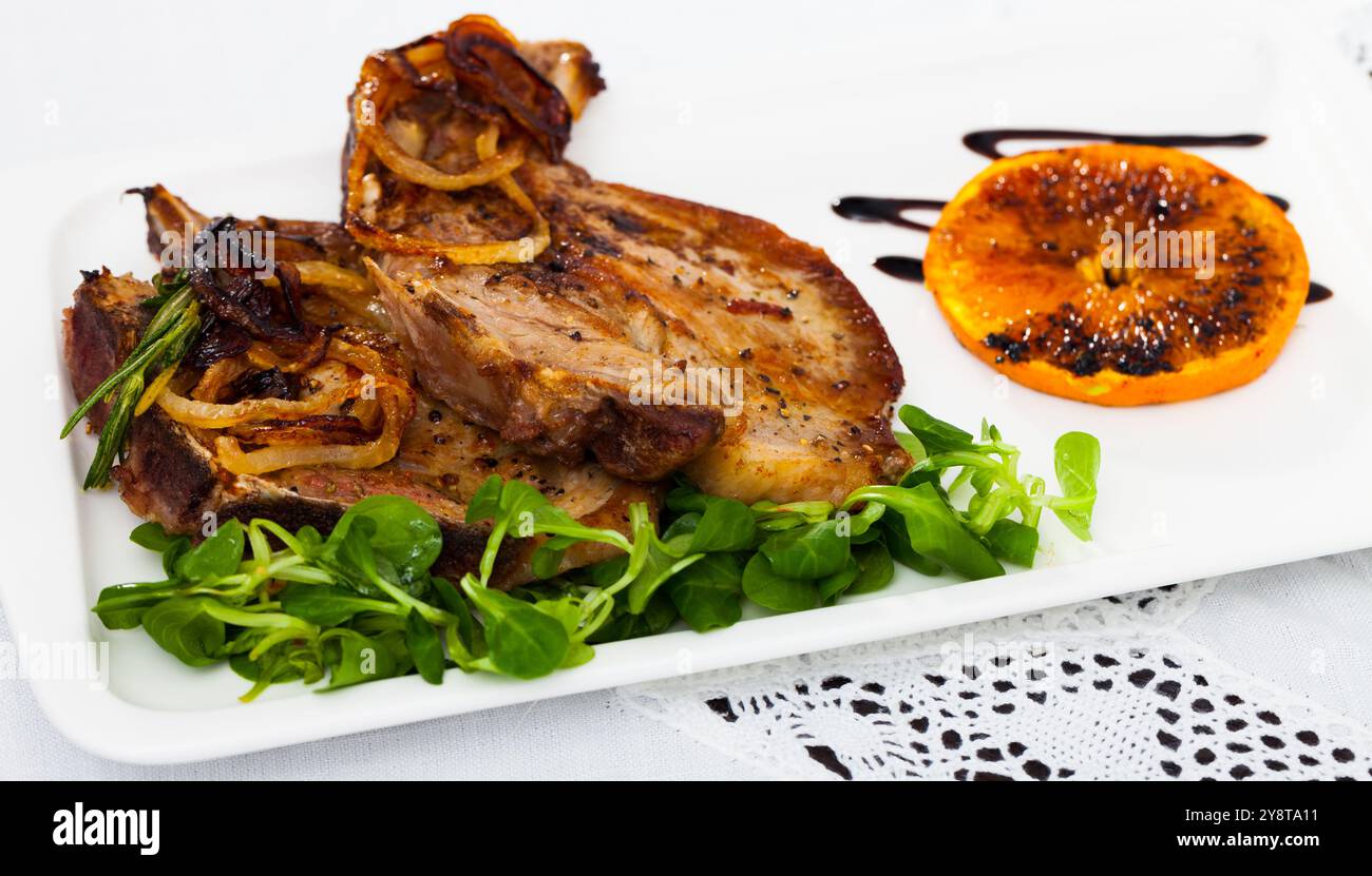 Cooked fried pork meat chop with herb, fried orange and onion slices ...