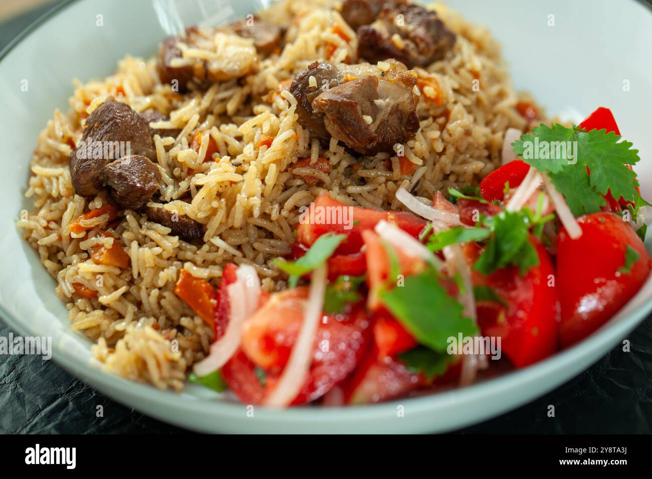 Traditional pilaf with stewed lamb and fresh tomato salad Stock Photo ...