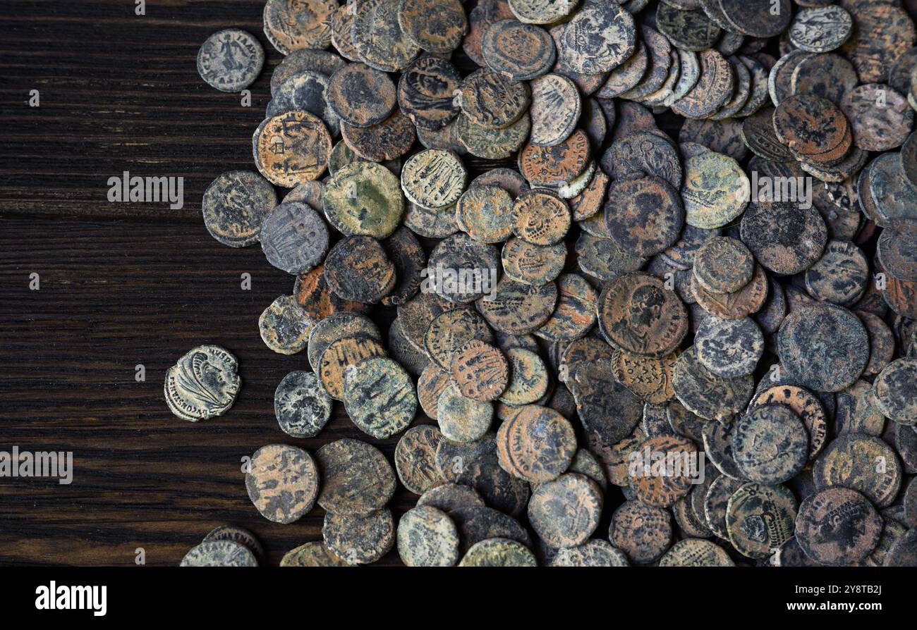 Pile of bronze Roman coins on old dark wooden table, top view of ...