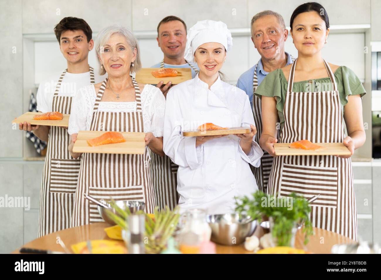Group portrait of female chef and his students in kitchen with cutting ...