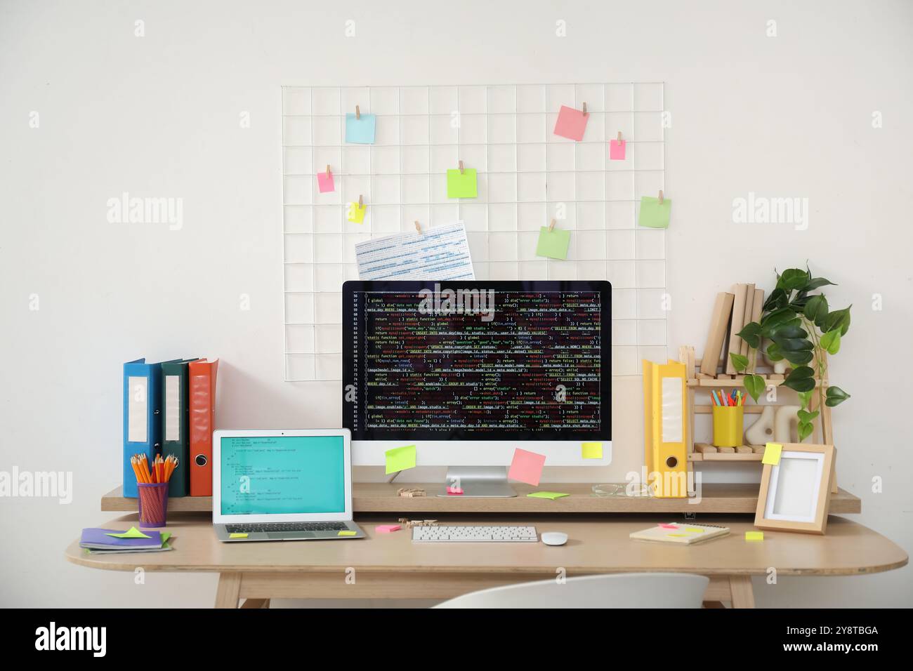 Computer monitor and laptop with codes on programmer's desk in light ...