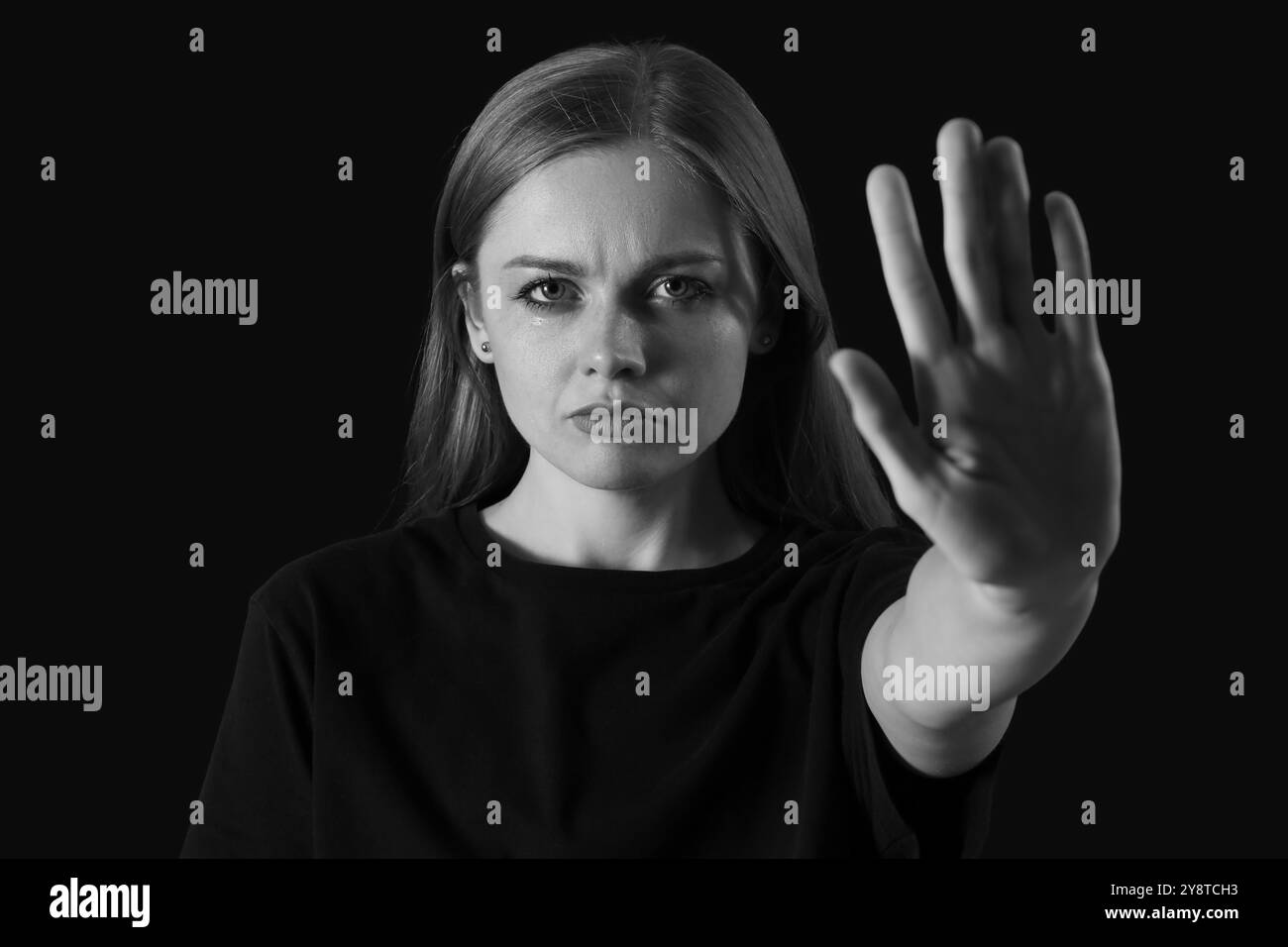 Crying young woman showing STOP gesture on black background Stock Photo ...
