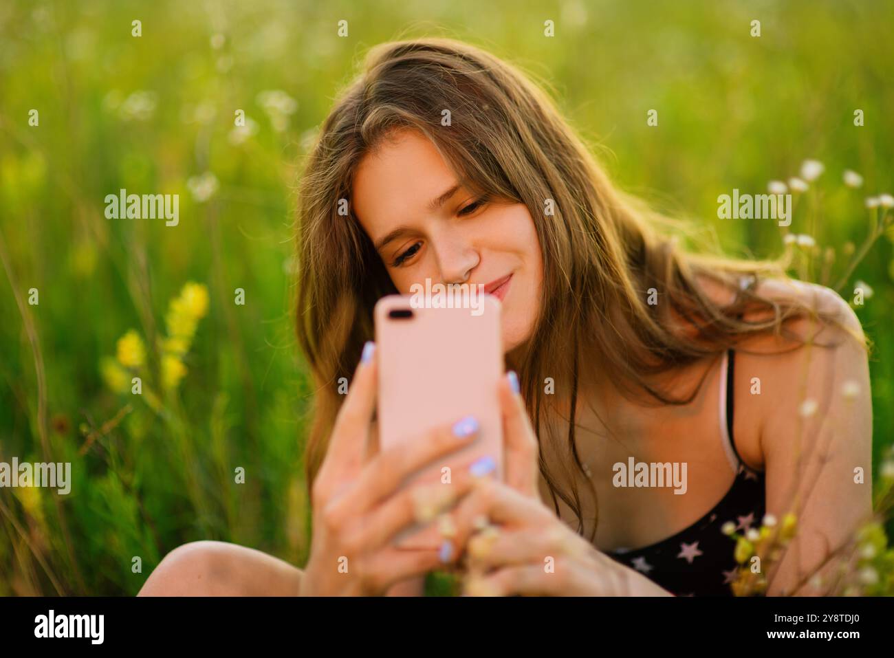 Young beautiful Generation Z girl using modern smartphone in a flower ...