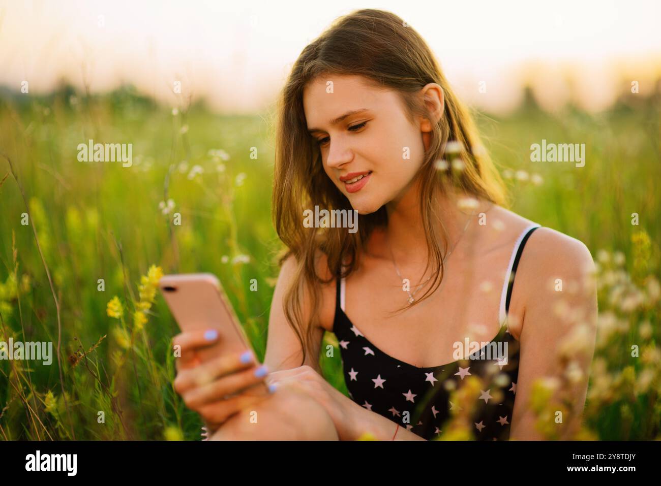 Young beautiful Generation Z girl using modern smartphone in a flower ...