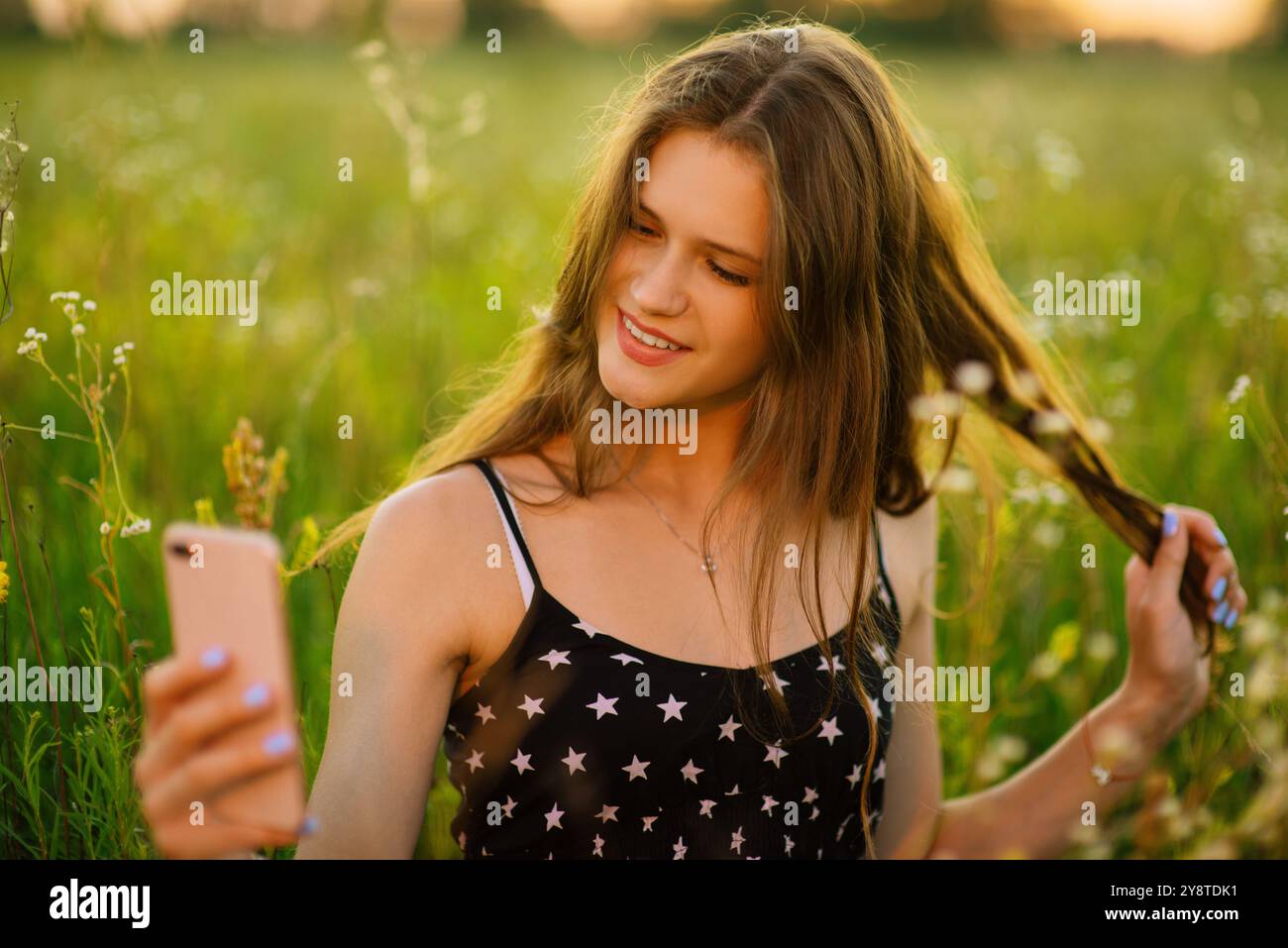 Young beautiful Generation Z girl using modern smartphone in a flower ...