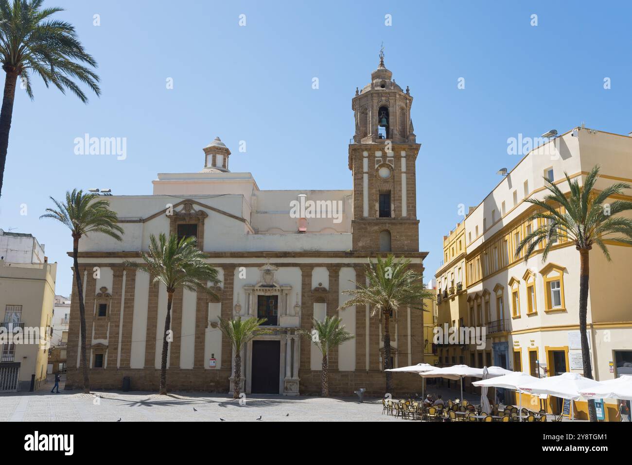 Historic cathedral with palm trees in a sunny square under a blue sky ...
