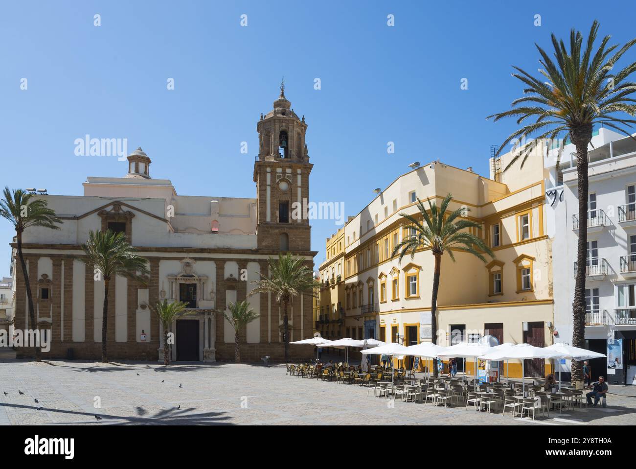 Historic cathedral on a sunny square with palm trees and blue sky ...