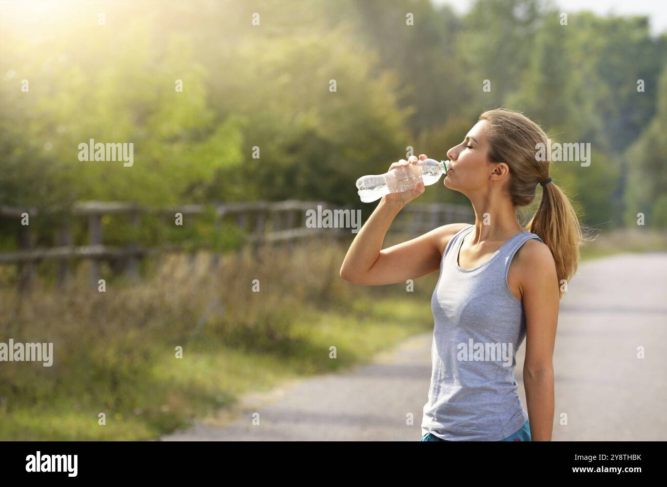 Young woman drink water while jogging outdoors Stock Photo - Alamy